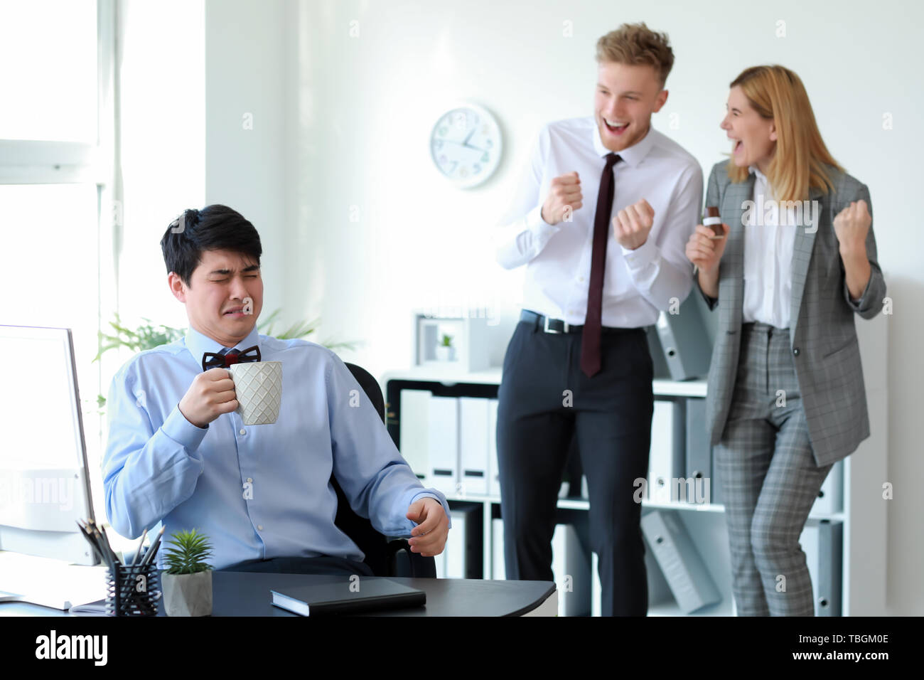 Friends playing a prank on their colleague in office. April Fools' Day ...
