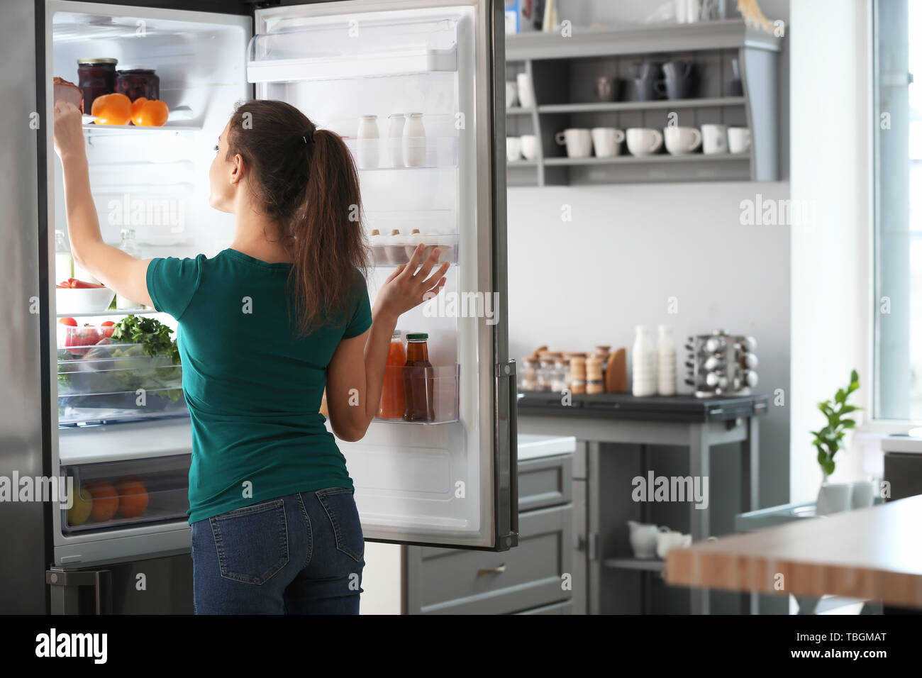 Woman taking food out of fridge at home Stock Photo - Alamy