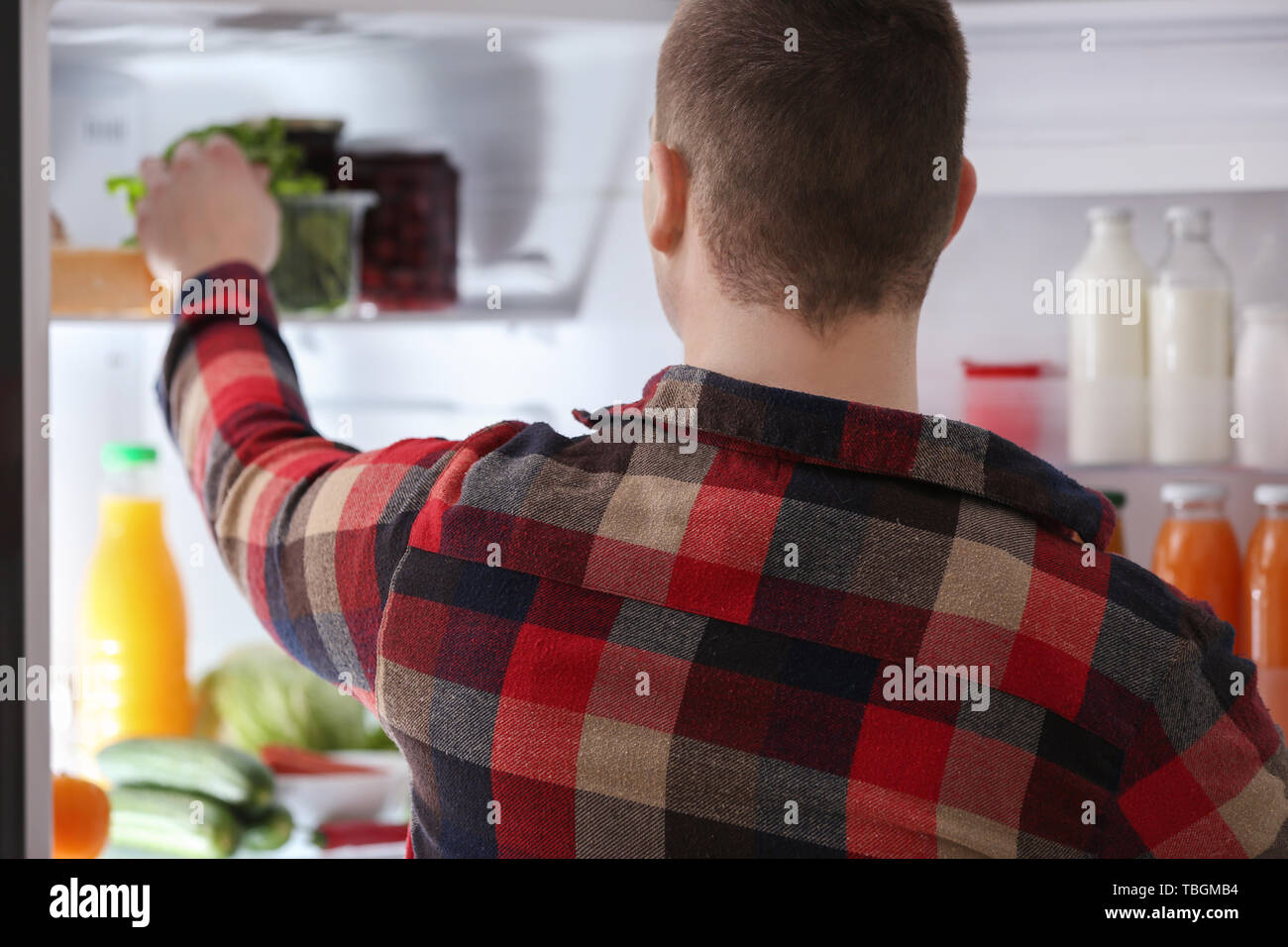 Man taking food out of fridge at home Stock Photo - Alamy