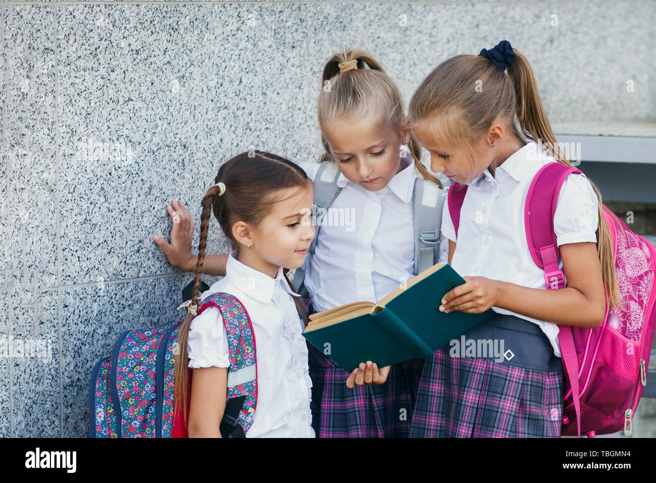Portrait of smiling school kids standing in school terrace and reading ...