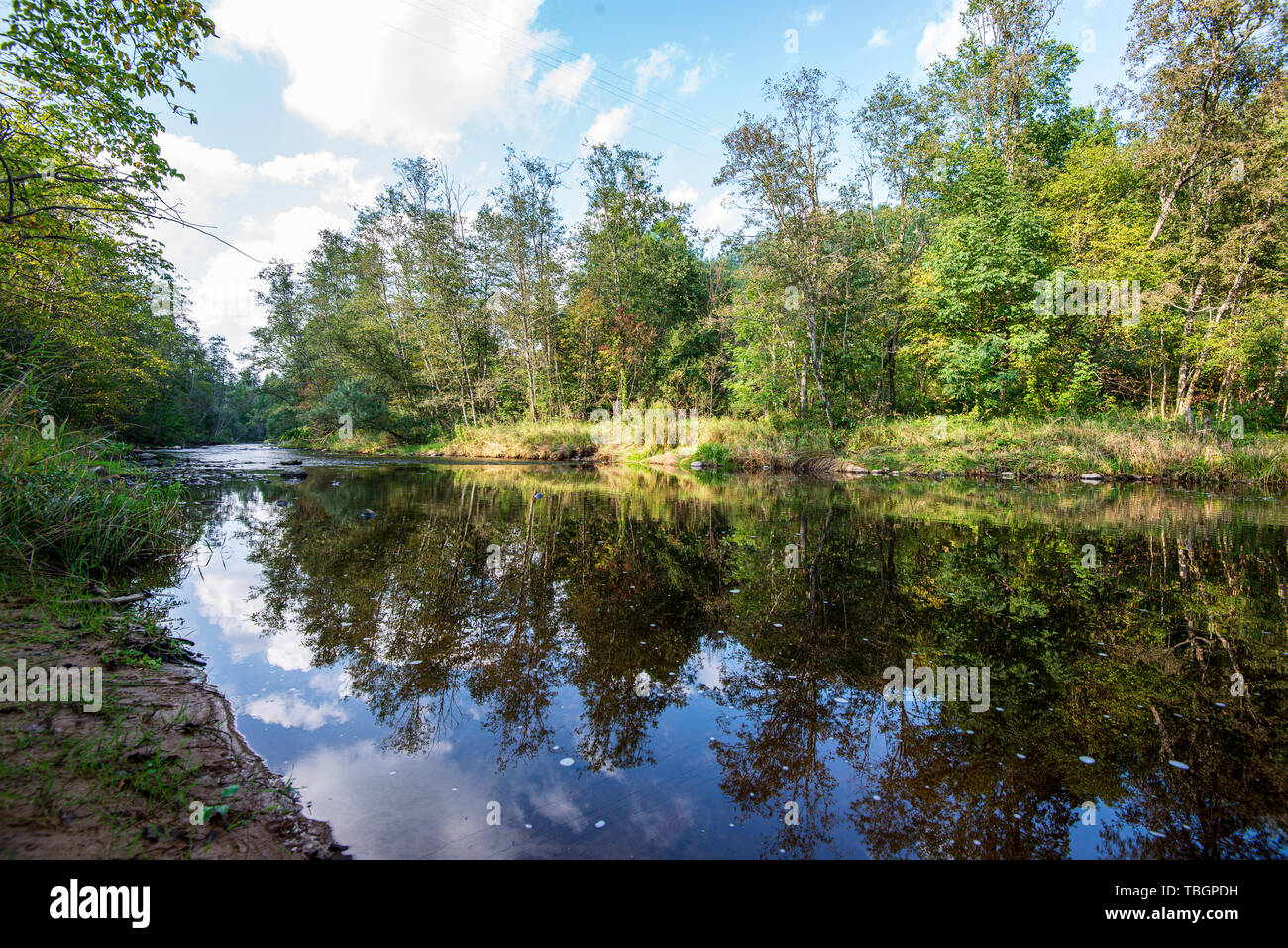 calm countryside lake river with cloud reflections in water and green ...
