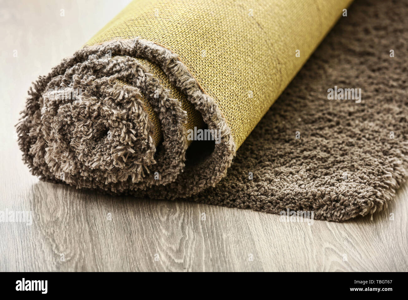 Rolled carpet on floor in room Stock Photo - Alamy