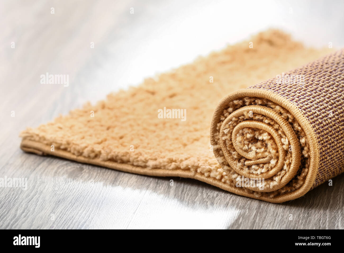 Rolled carpet on floor in room Stock Photo - Alamy