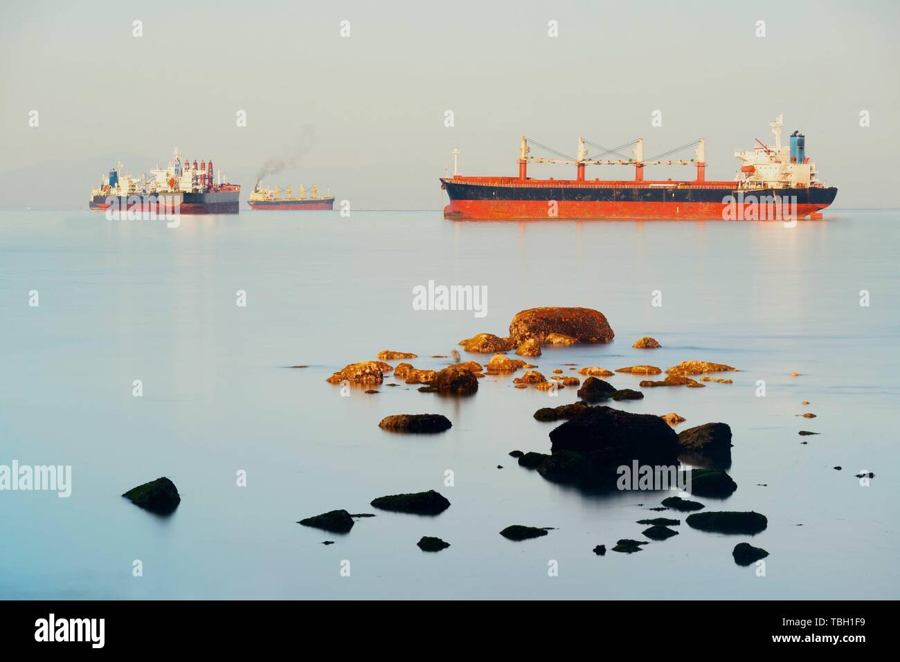 Cargo ship and rock in sea at sunrise in Vancouver Stock Photo - Alamy