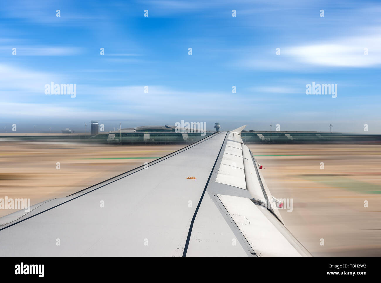 Airplane running on the airport runway, wing seen through the porthole ...