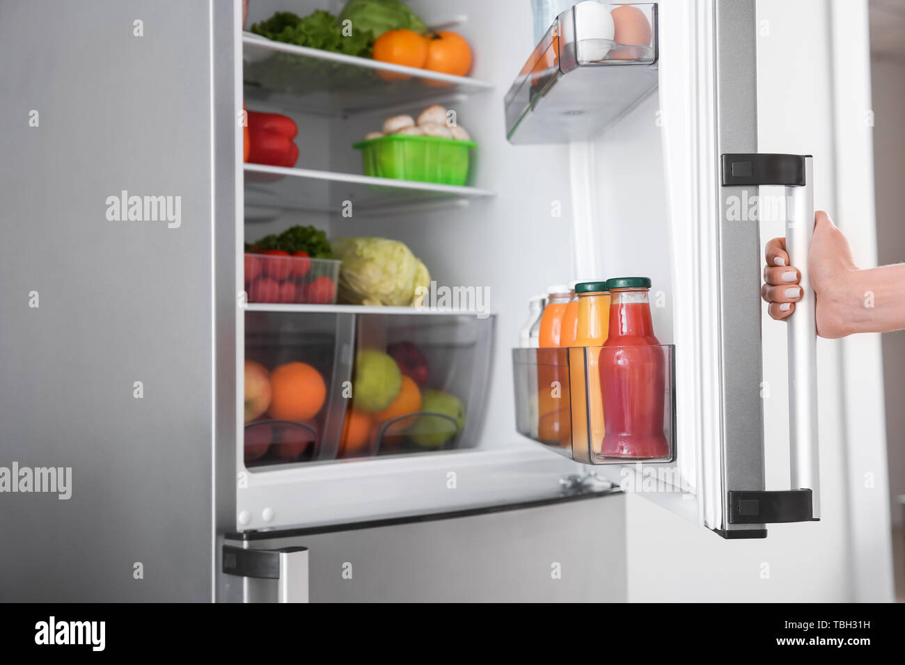 Woman opening modern fridge Stock Photo - Alamy