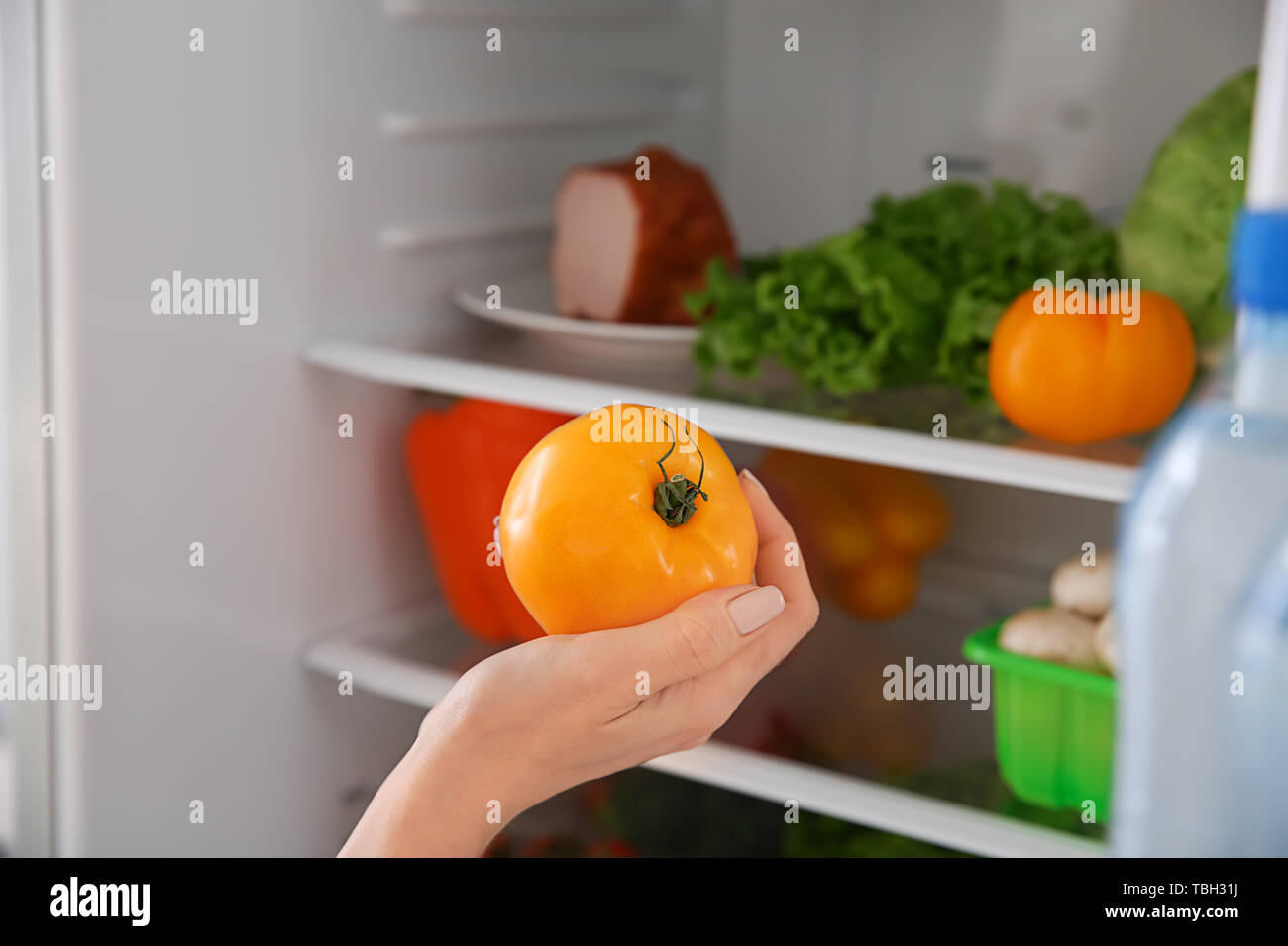 Woman taking tomato from fridge Stock Photo - Alamy