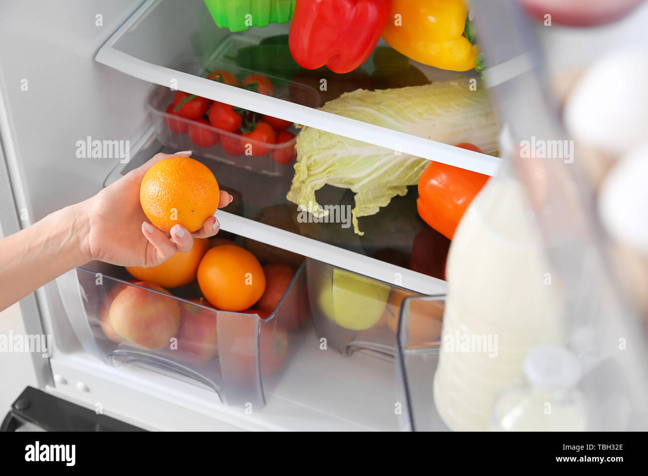 Woman taking fruit from fridge Stock Photo - Alamy