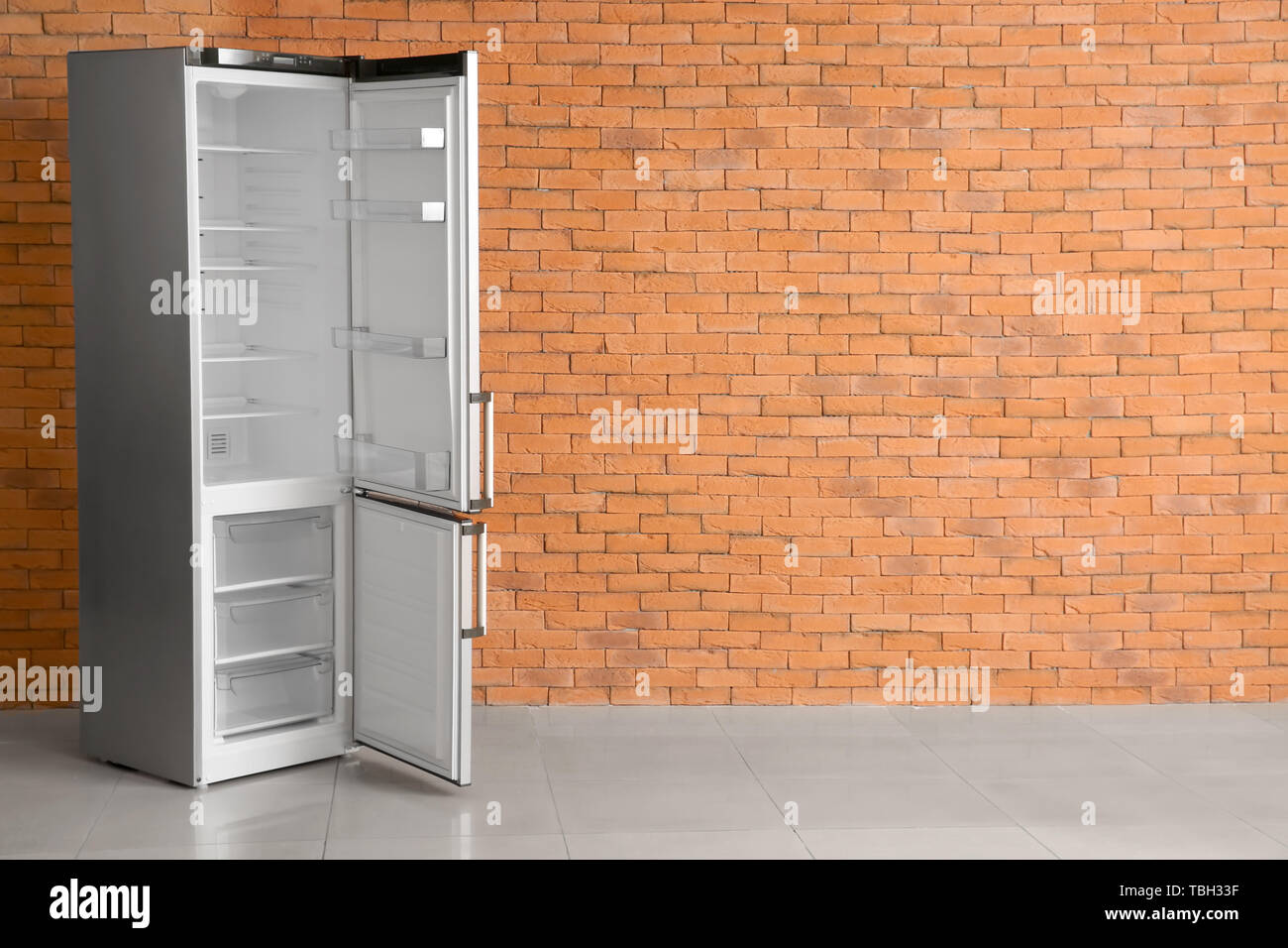 Open empty fridge near brick wall Stock Photo - Alamy
