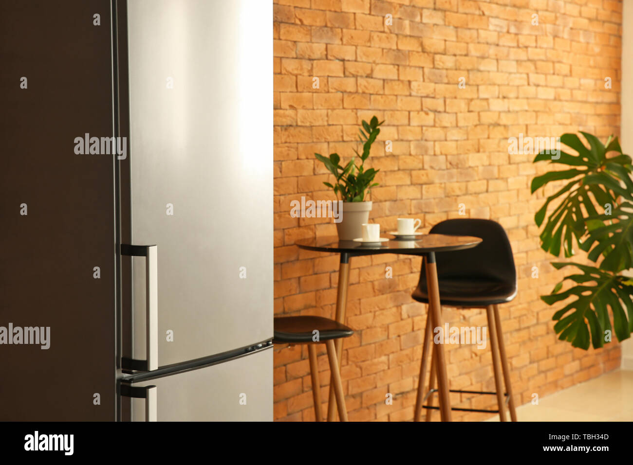 Modern fridge, table and chairs in kitchen Stock Photo - Alamy