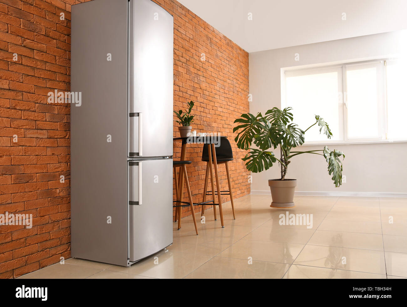 Modern fridge, table and chairs in kitchen Stock Photo - Alamy