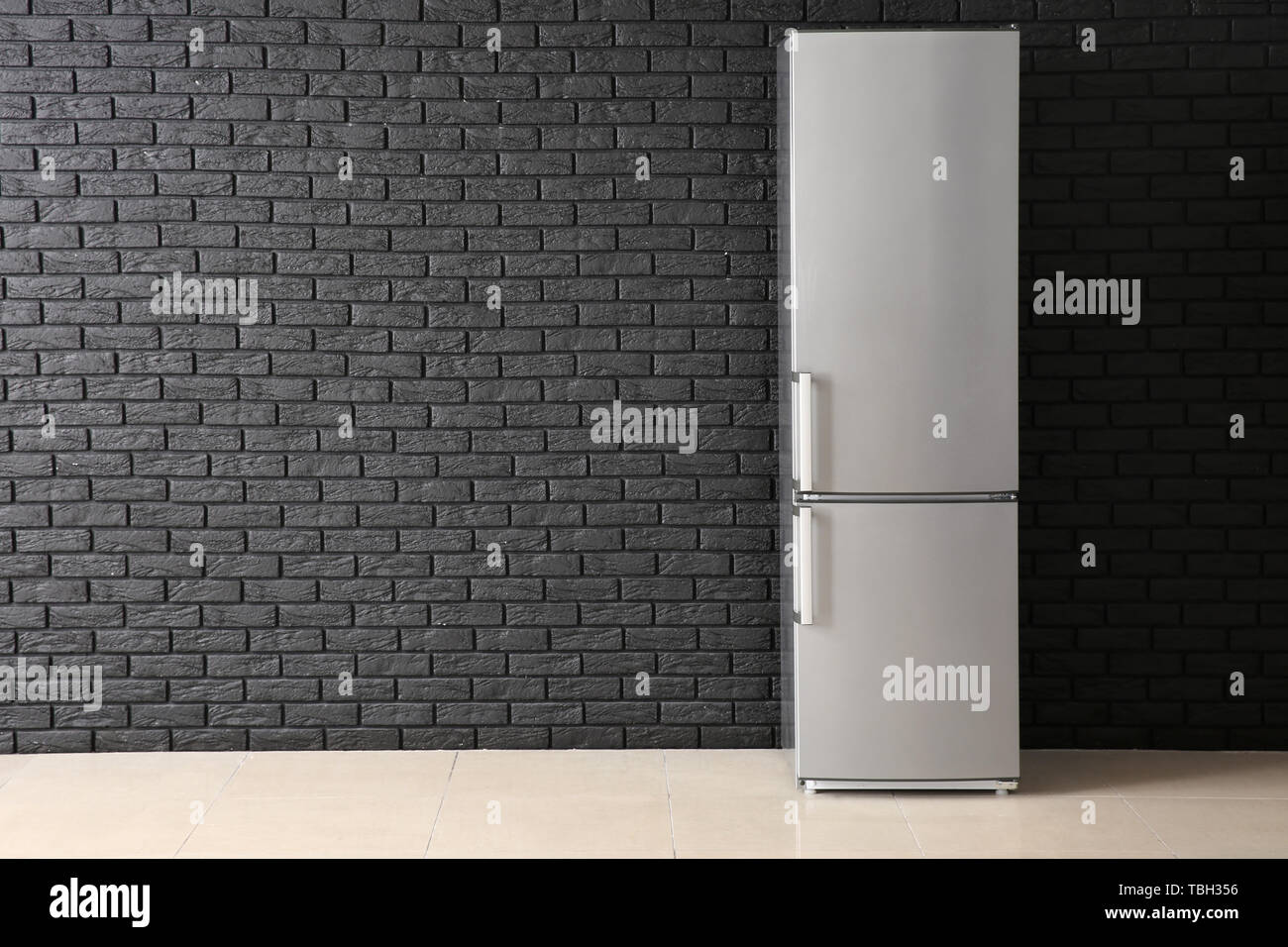 Modern fridge near dark brick wall Stock Photo - Alamy