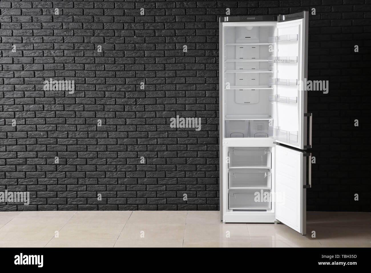 Open empty fridge near dark brick wall Stock Photo - Alamy