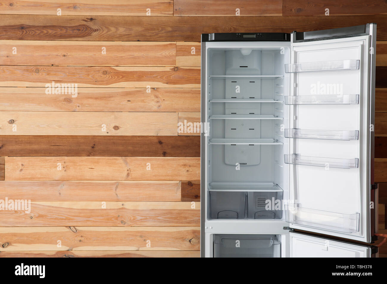 Open empty fridge near wooden wall Stock Photo - Alamy