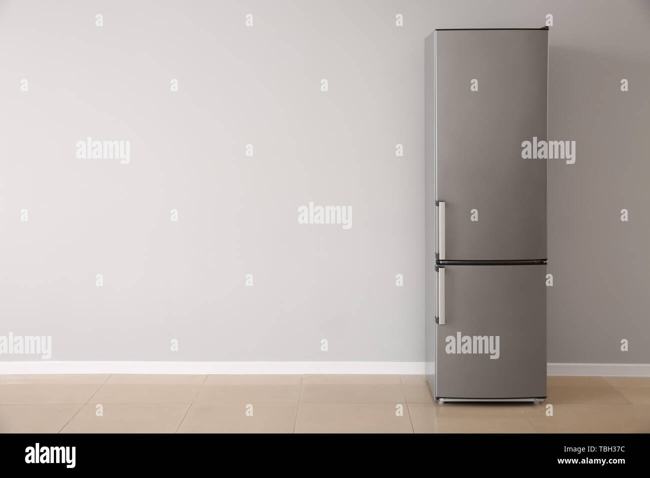 Modern fridge near white wall Stock Photo - Alamy