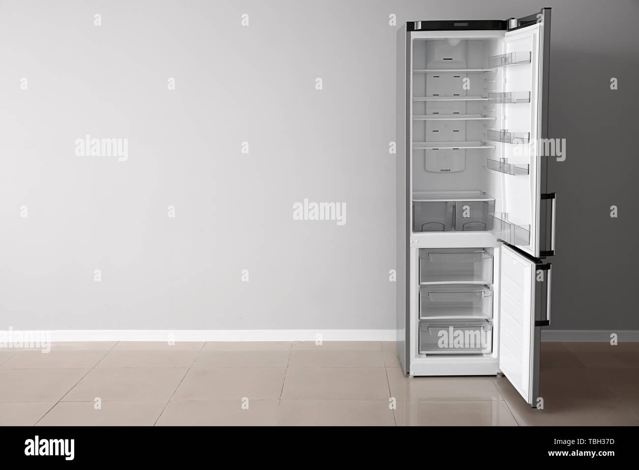 Open empty fridge near light wall Stock Photo - Alamy