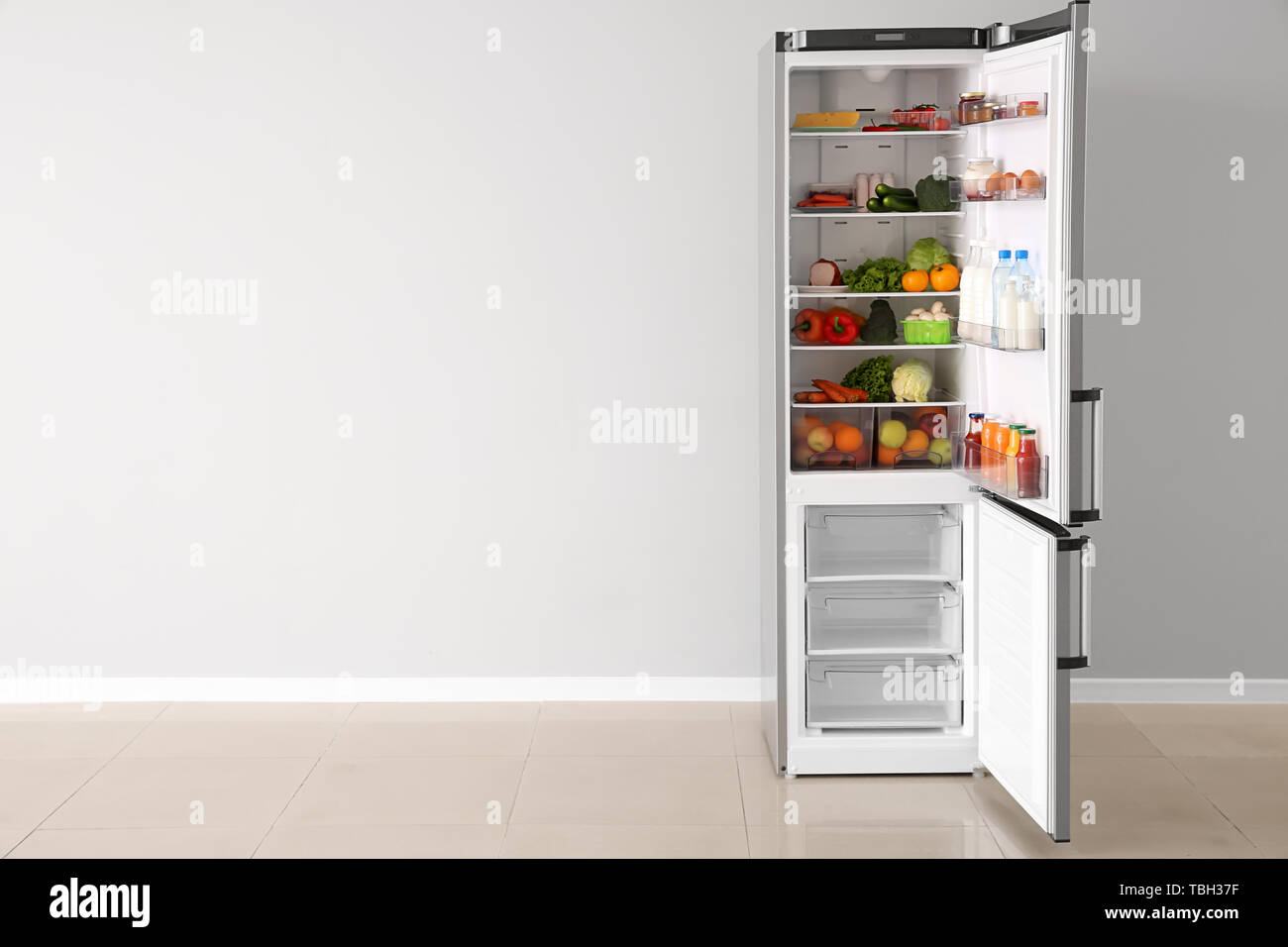 Open fridge full of food near white wall Stock Photo - Alamy