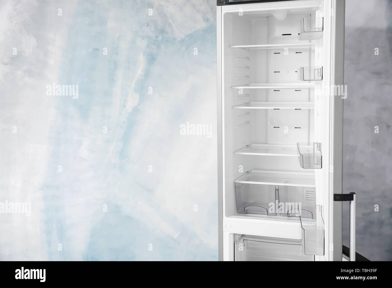 Open empty fridge near light wall Stock Photo - Alamy