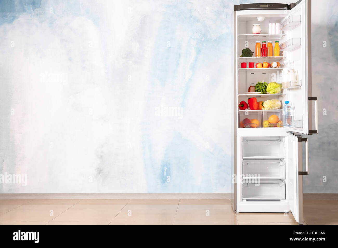 Open fridge full of food near color wall Stock Photo - Alamy