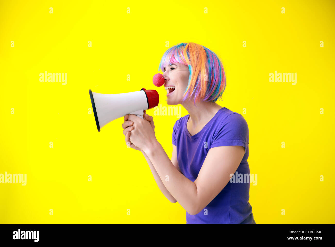Funny woman with megaphone on color background. April Fools' Day prank ...