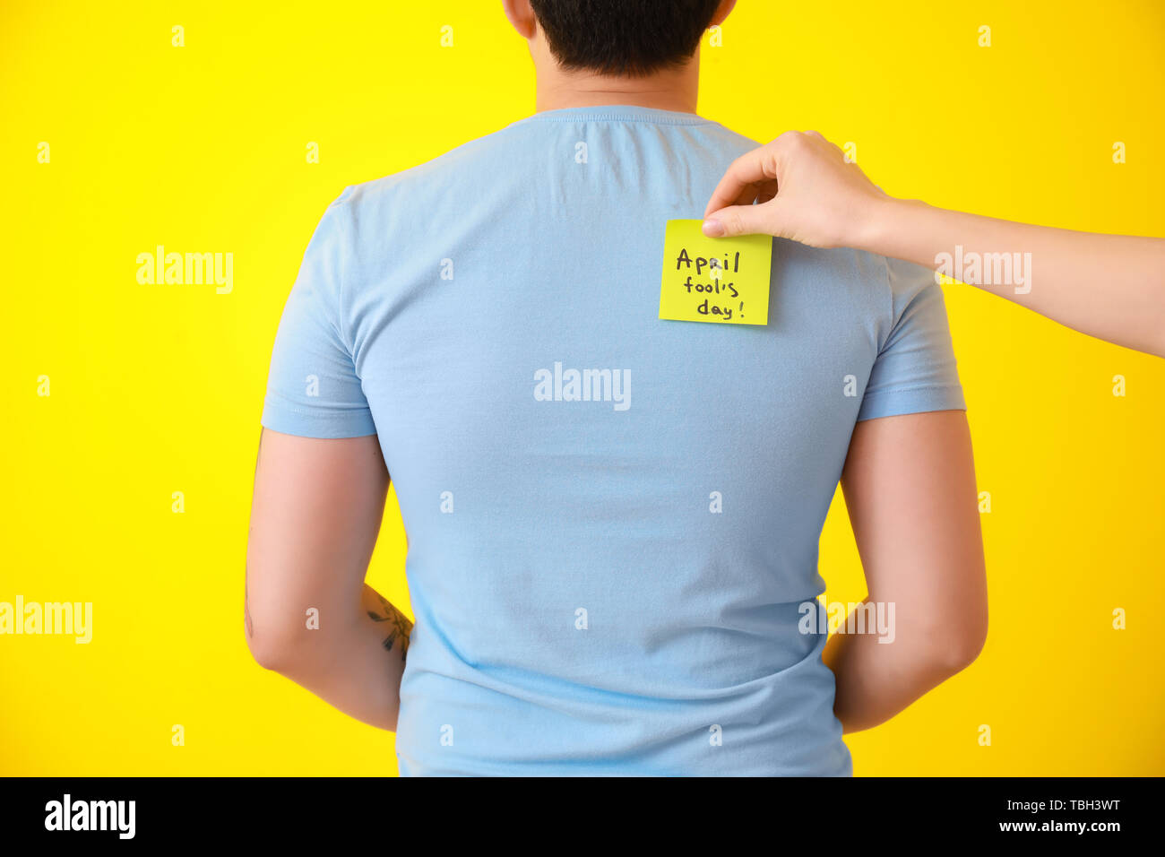 Woman sticking paper to her friend's back against color background ...