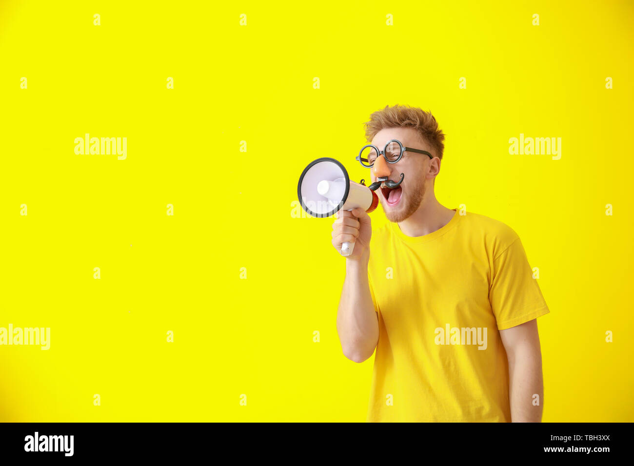 Funny man with megaphone on color background. April Fools' Day prank ...