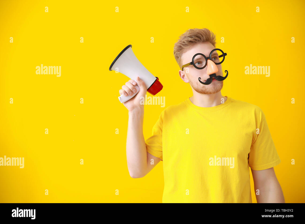 Funny man with megaphone on color background. April Fools' Day prank ...
