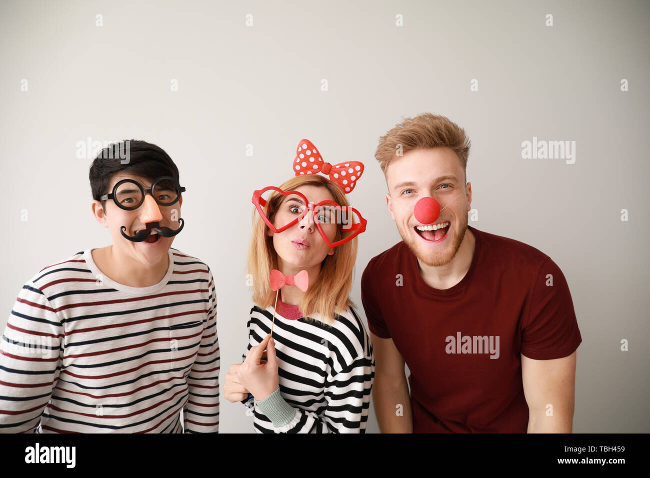 Funny friends with party decor for April Fools' Day on light background ...