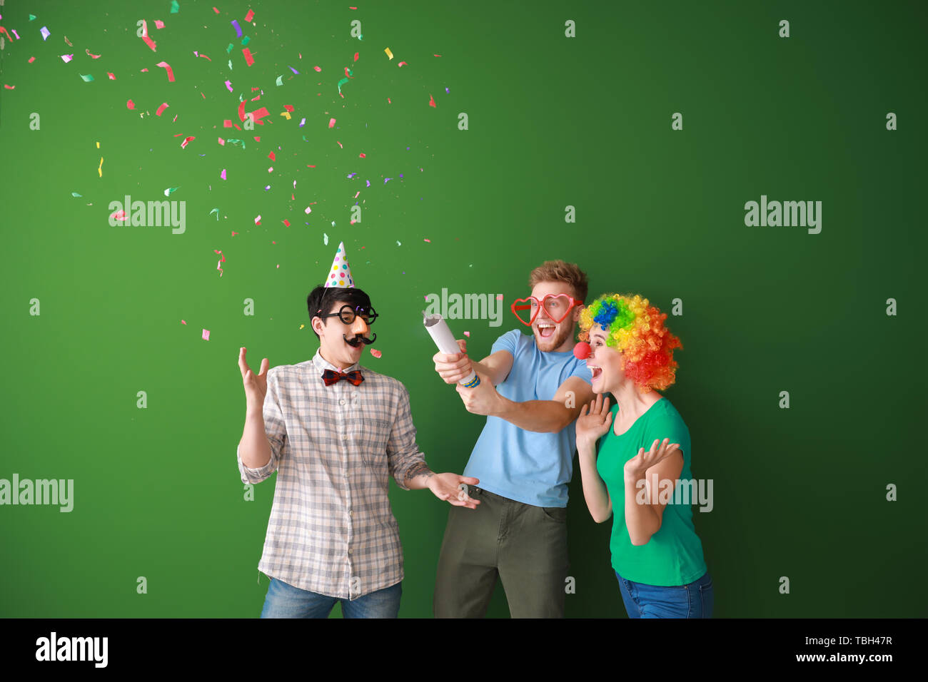 Funny man with party decor and confetti for April Fools' Day on color ...