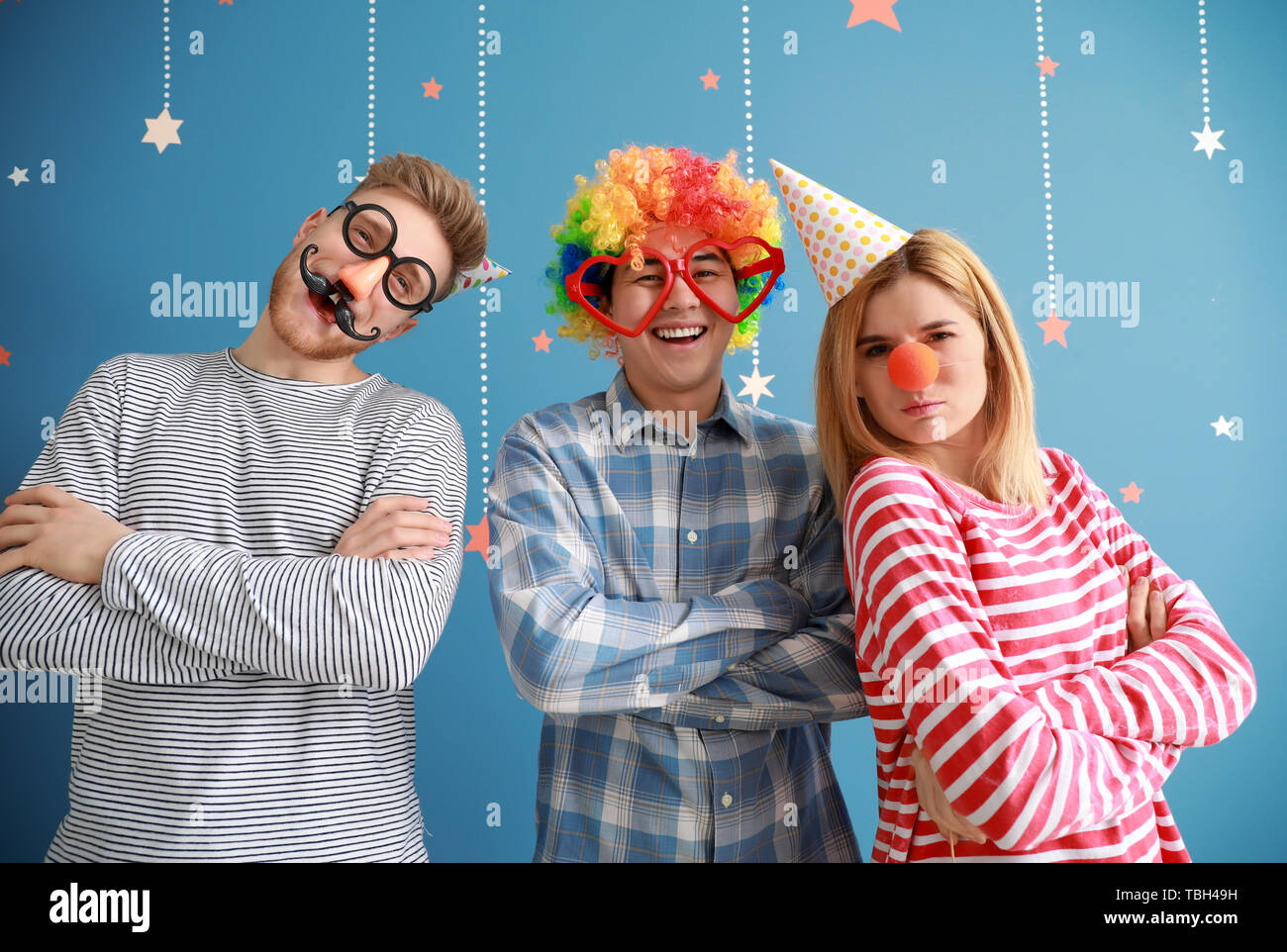 Funny friends with party decor for April Fools' Day on color background ...
