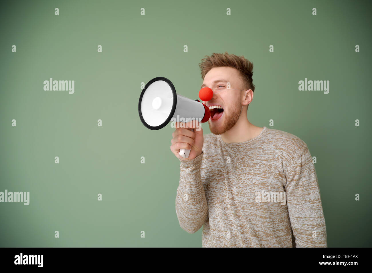 Funny man with megaphone on color background. April Fools' Day prank ...