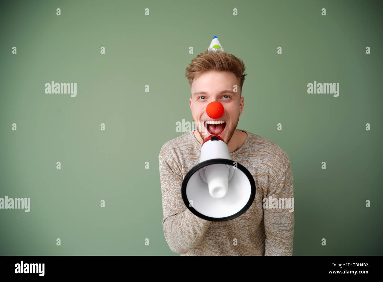 Funny man with megaphone on color background. April Fools' Day prank ...
