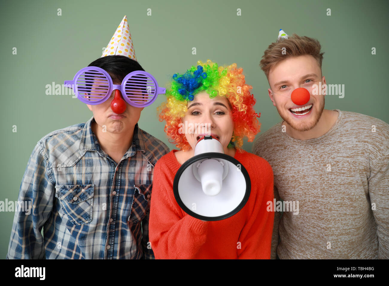 Funny friends with megaphone on color background. April Fools' Day ...