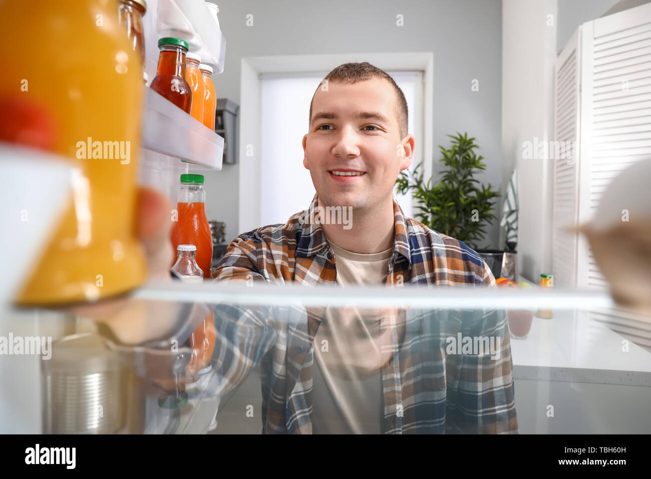 Man taking food out of fridge at home, view from inside Stock Photo - Alamy