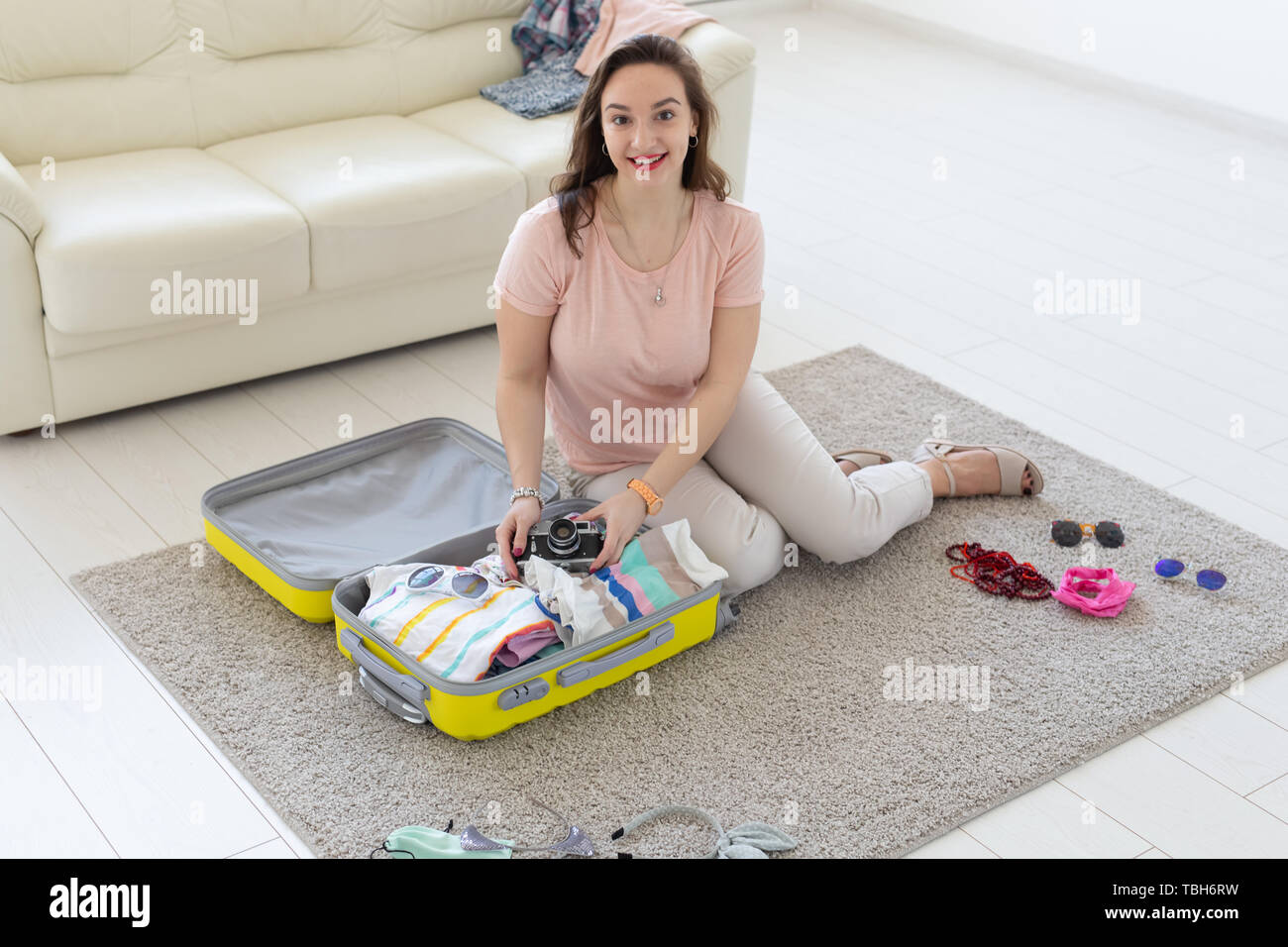 Vacation, journey and holidays concept - woman collecting clothes on ...