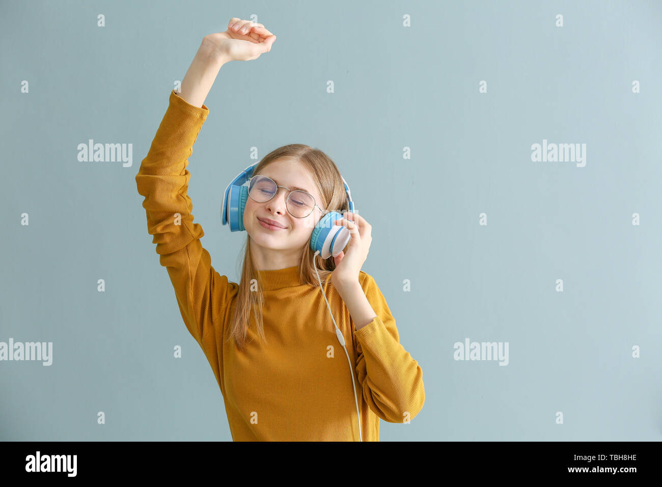 Cute teenage girl listening to music on color background Stock Photo ...