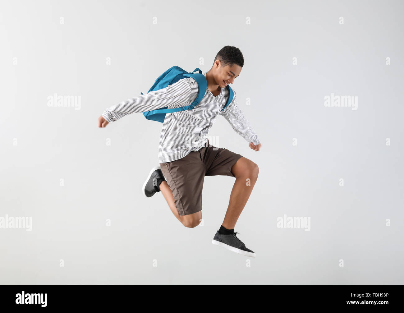 Portrait of jumping African-American teenage boy on grey background ...