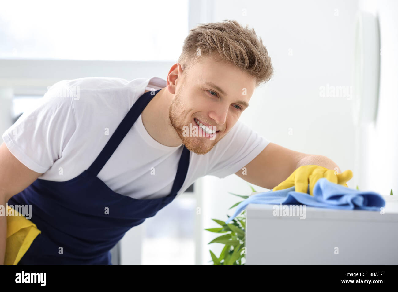 Male janitor cleaning shelf in office Stock Photo - Alamy
