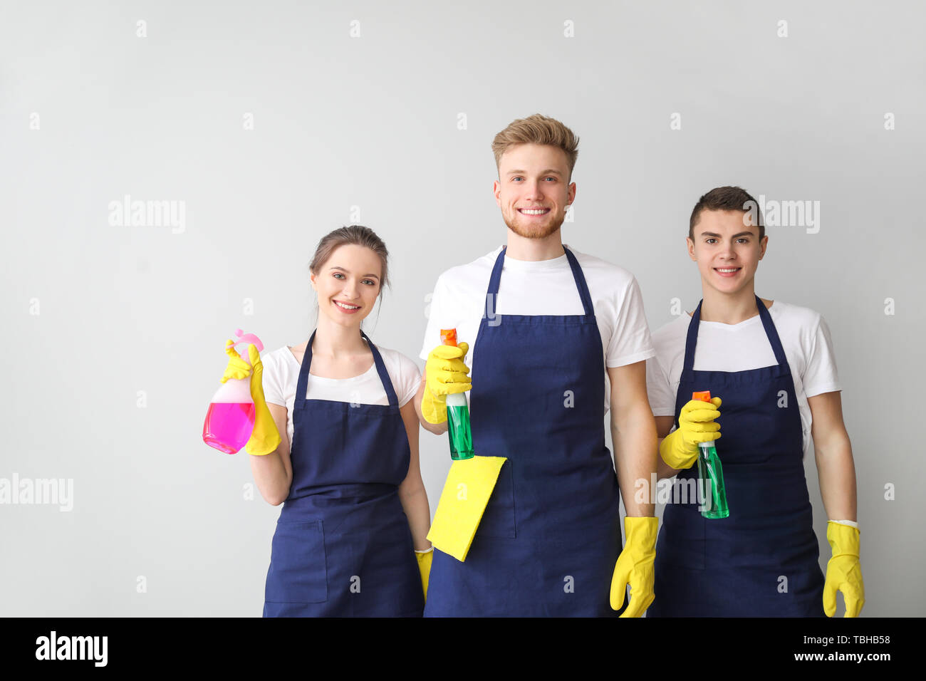Portrait of janitors with bottles of detergent on light background ...