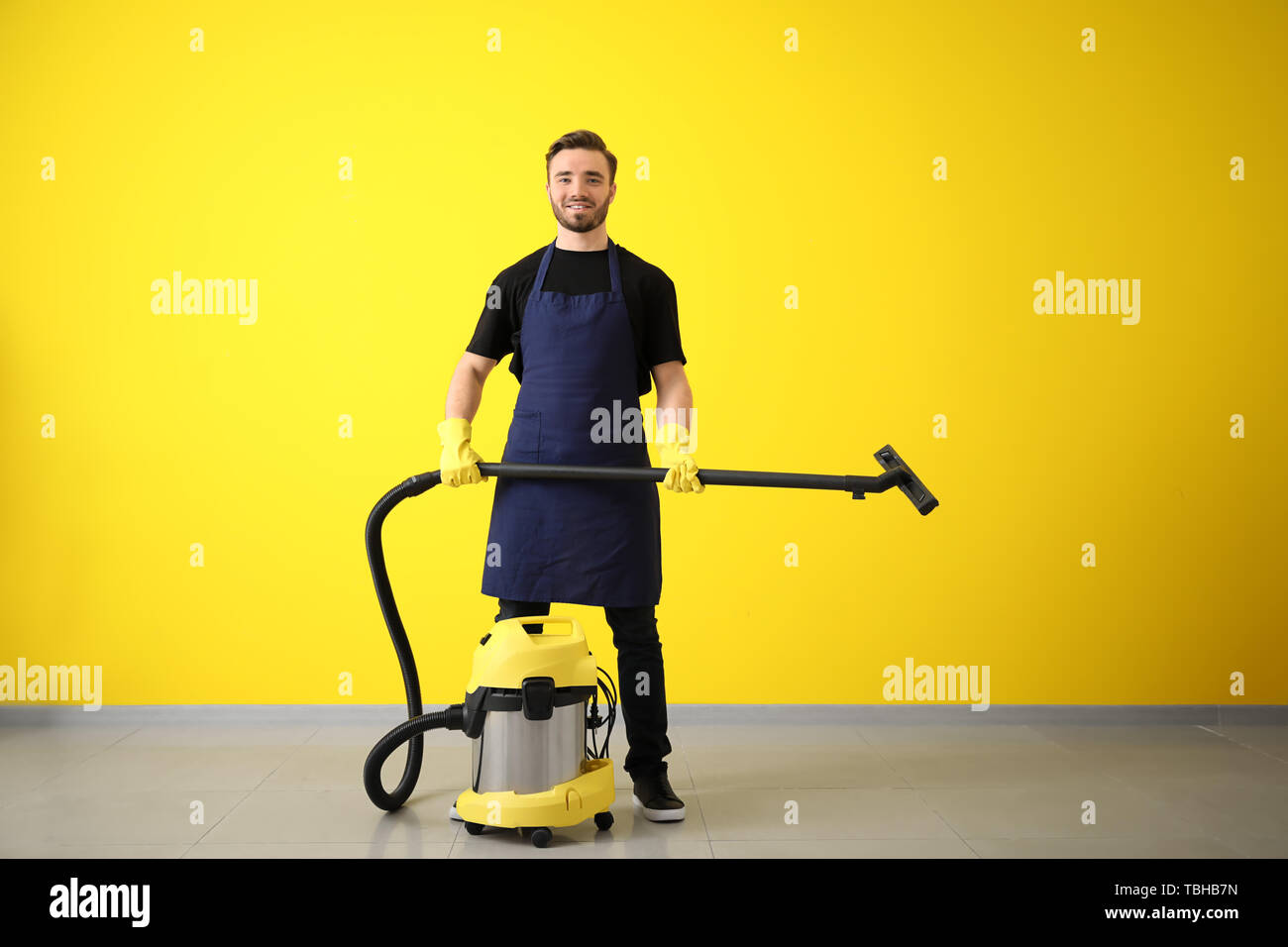 Portrait of male janitor with vacuum cleaner near color wall Stock ...