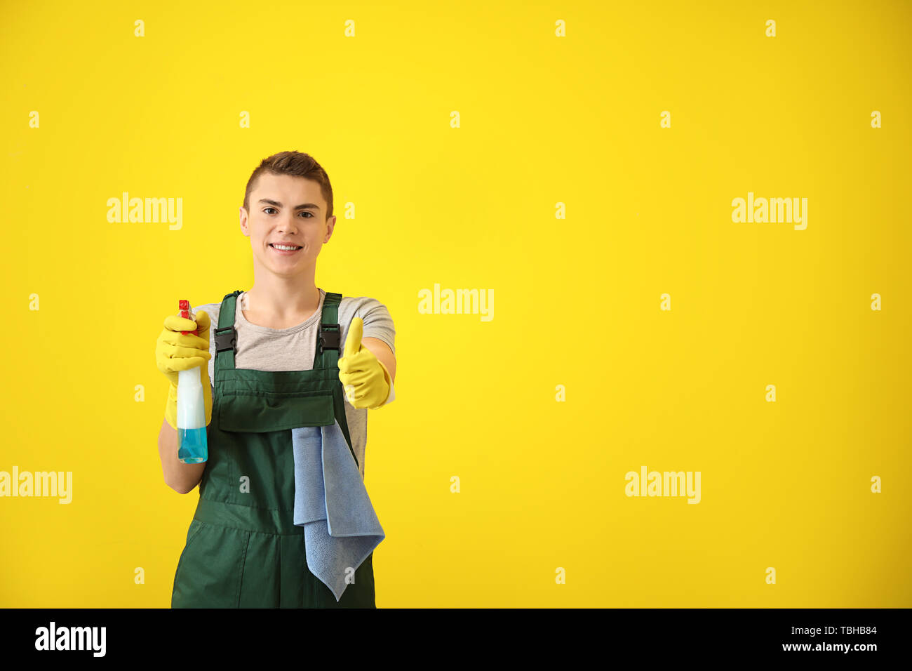 Portrait of male janitor showing thumb-up gesture on color background ...