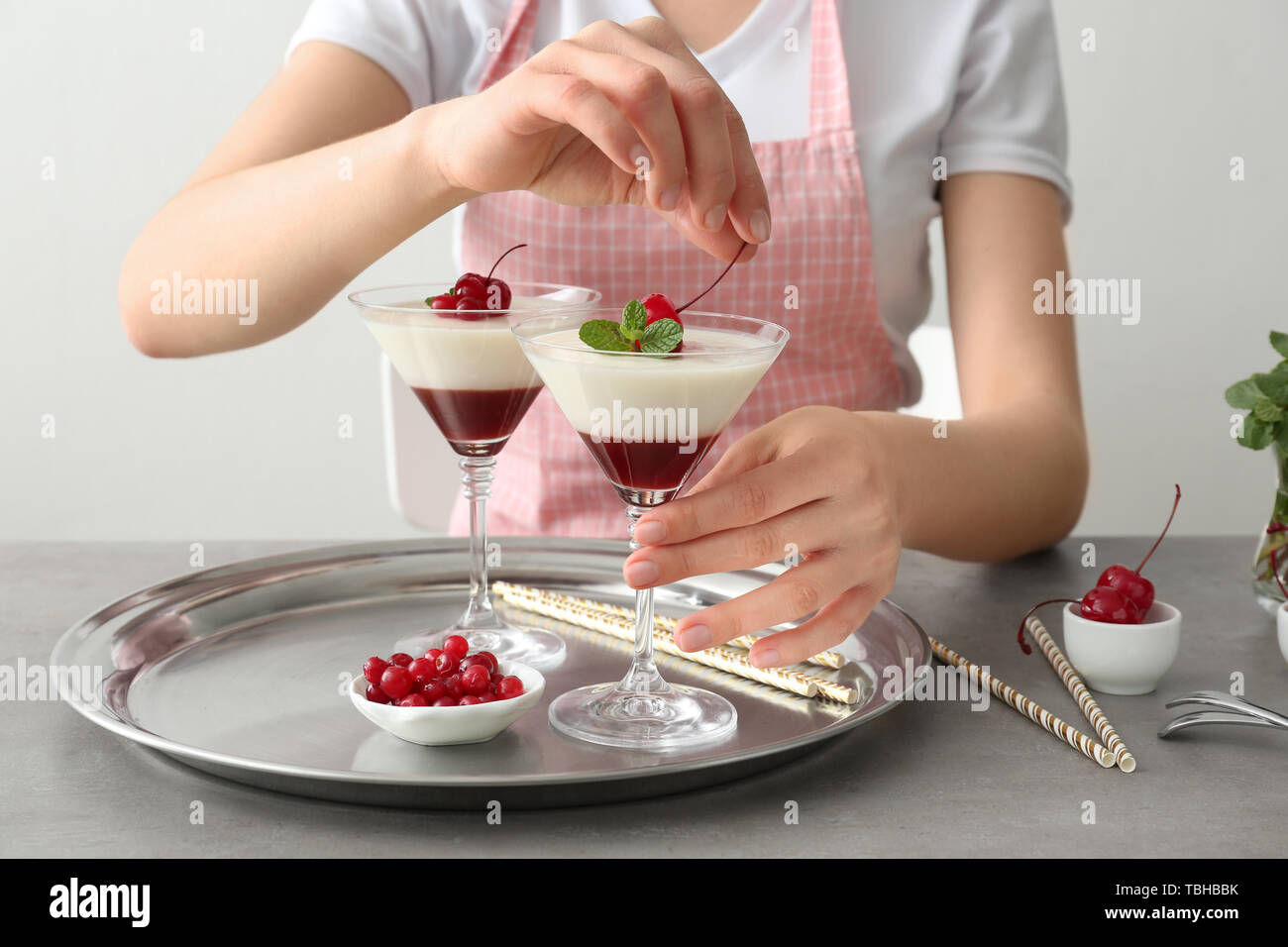 Woman decorating tasty panna cotta at table Stock Photo - Alamy