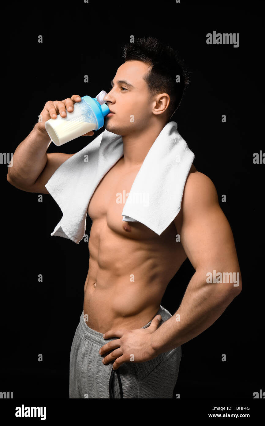 Sporty man drinking protein shake on dark background Stock Photo - Alamy