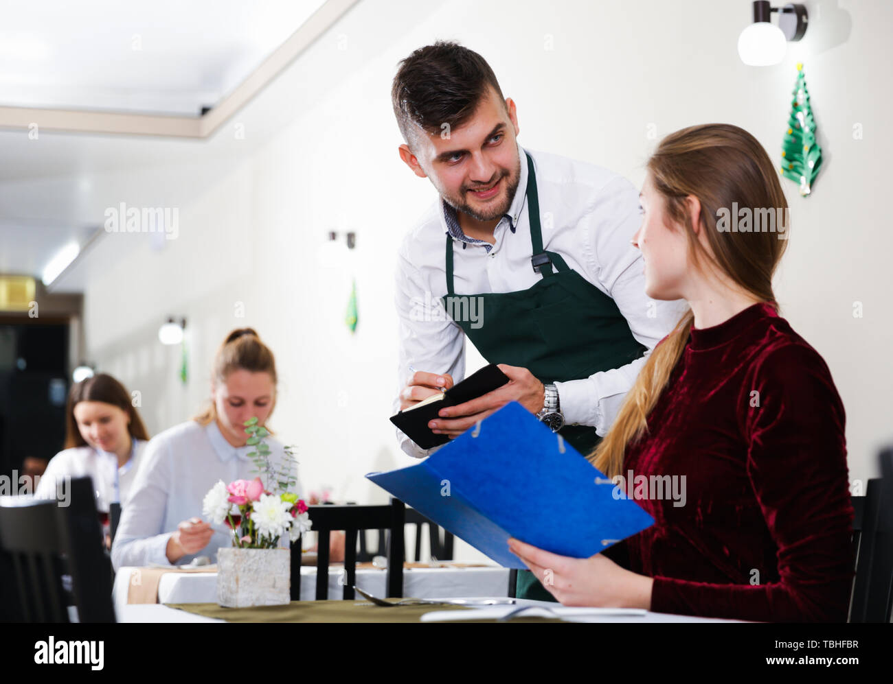 Welcoming waiter is taking order from cheerful woman in restaurante ...