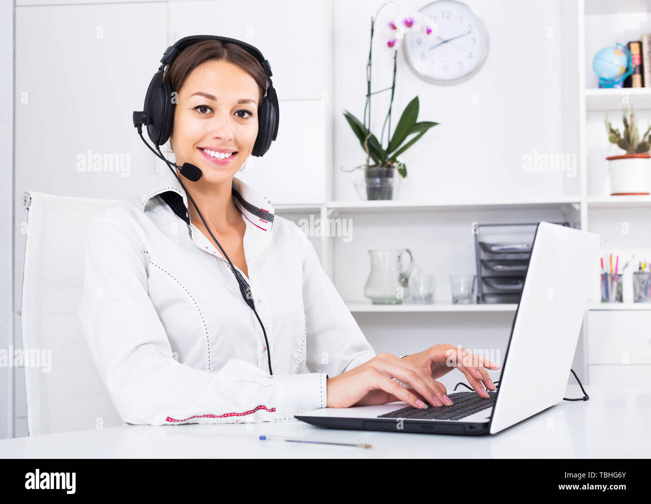 Positive woman talking with customer using hands-free set at call ...