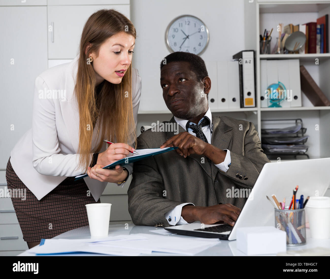 Attractive Caucasian secretary helping African American boss and ...