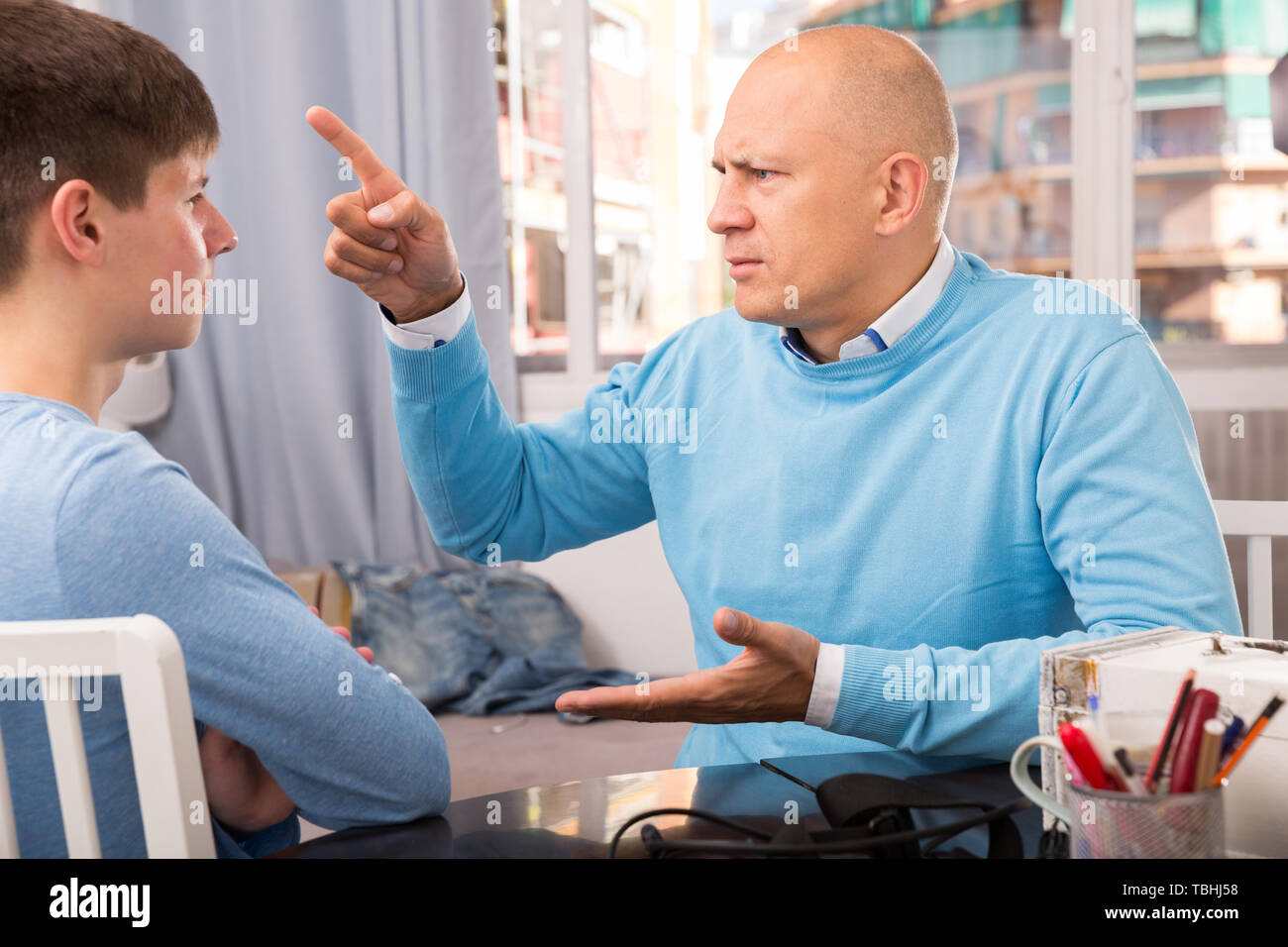 Portrait of angry man scolding teenage son in living room at home Stock ...