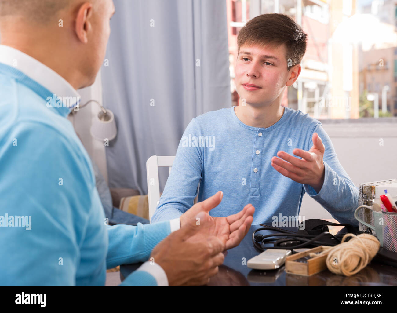 Teenage son talking to father, having friendly conversation at home ...