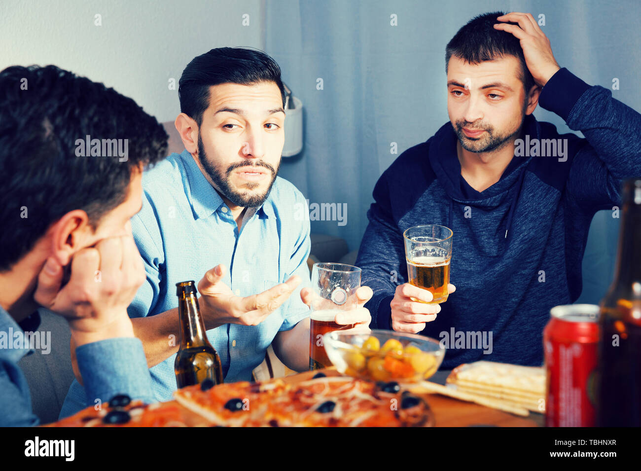 adult anxious men discussing problems while drinking beer with pizza at ...