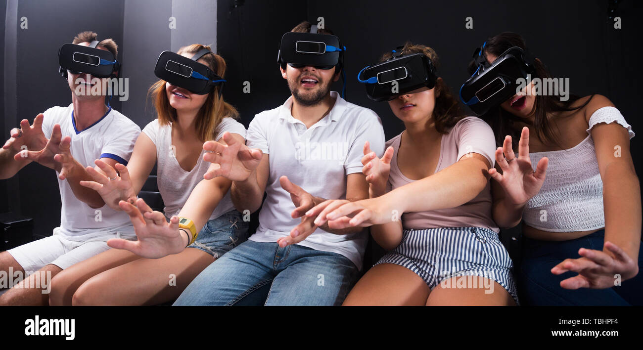 Young people wearing virtual reality goggles playing video games ...